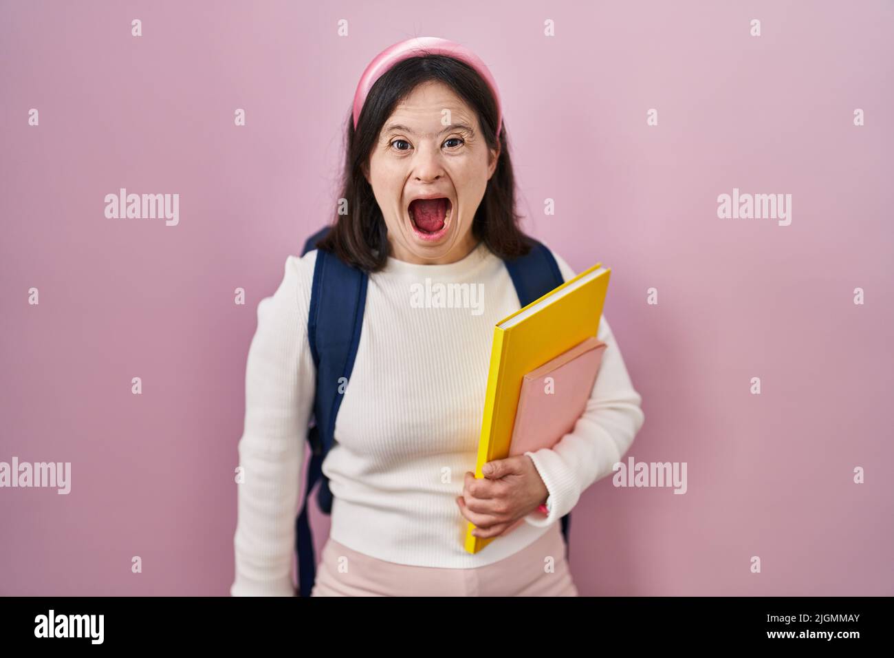 Woman with down syndrome wearing student backpack and holding books ...