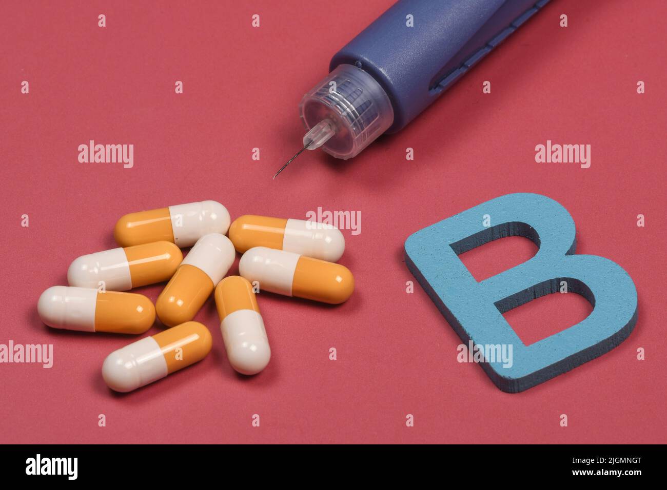 yellow and white medicine capsules on red background and insulin pen ...