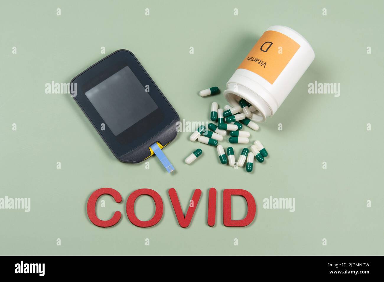 device to measure blood glucose, vitamin D box and the word Covid ...