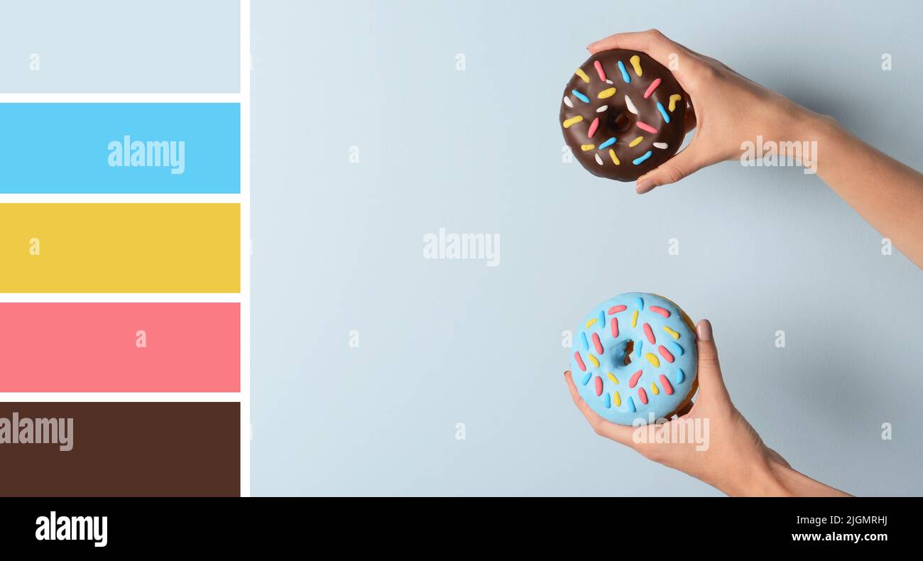 Hands with sweet donuts on light background. Different color patterns ...
