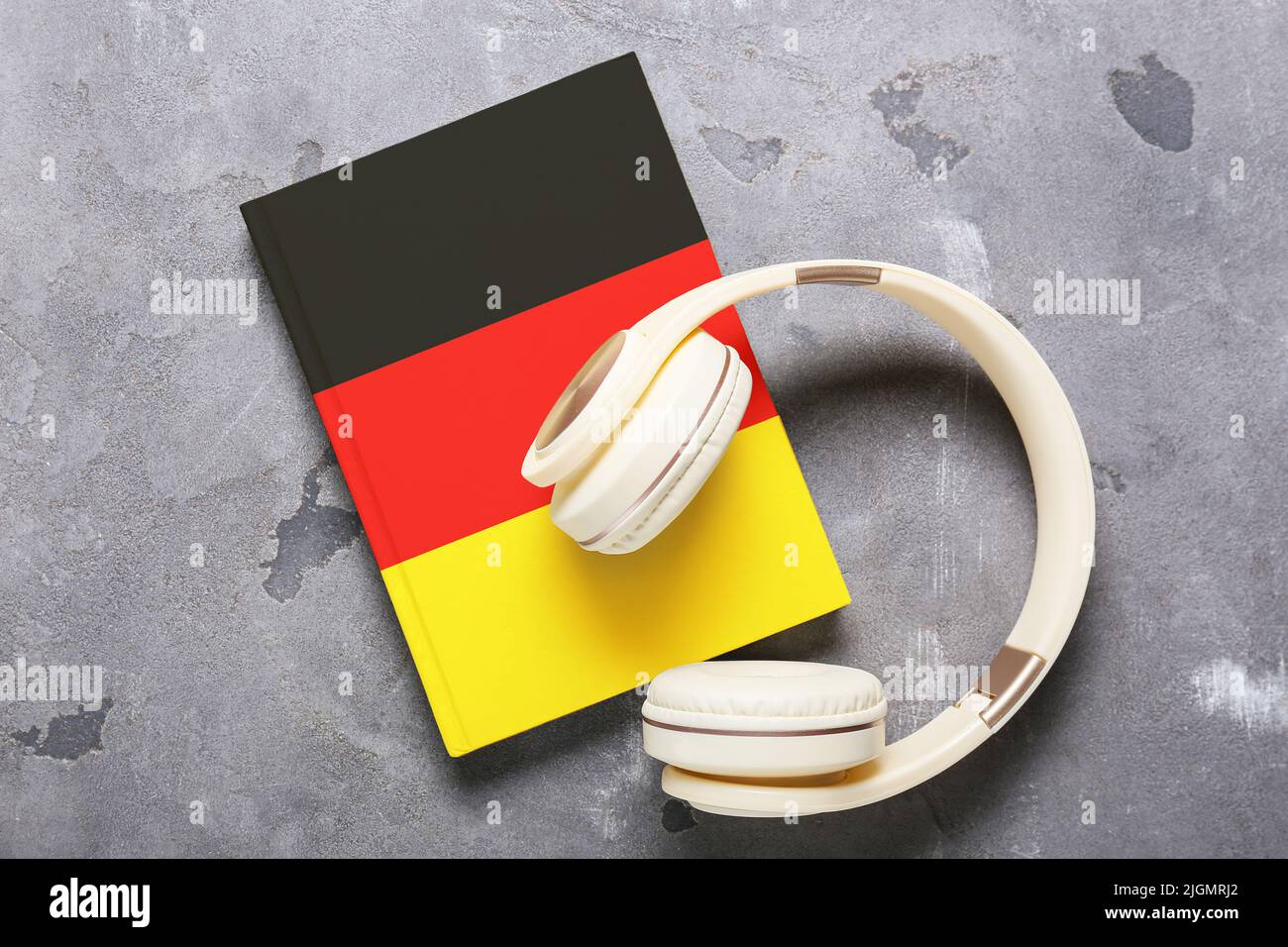 Modern headphones and book on grey background. Concept of studying ...