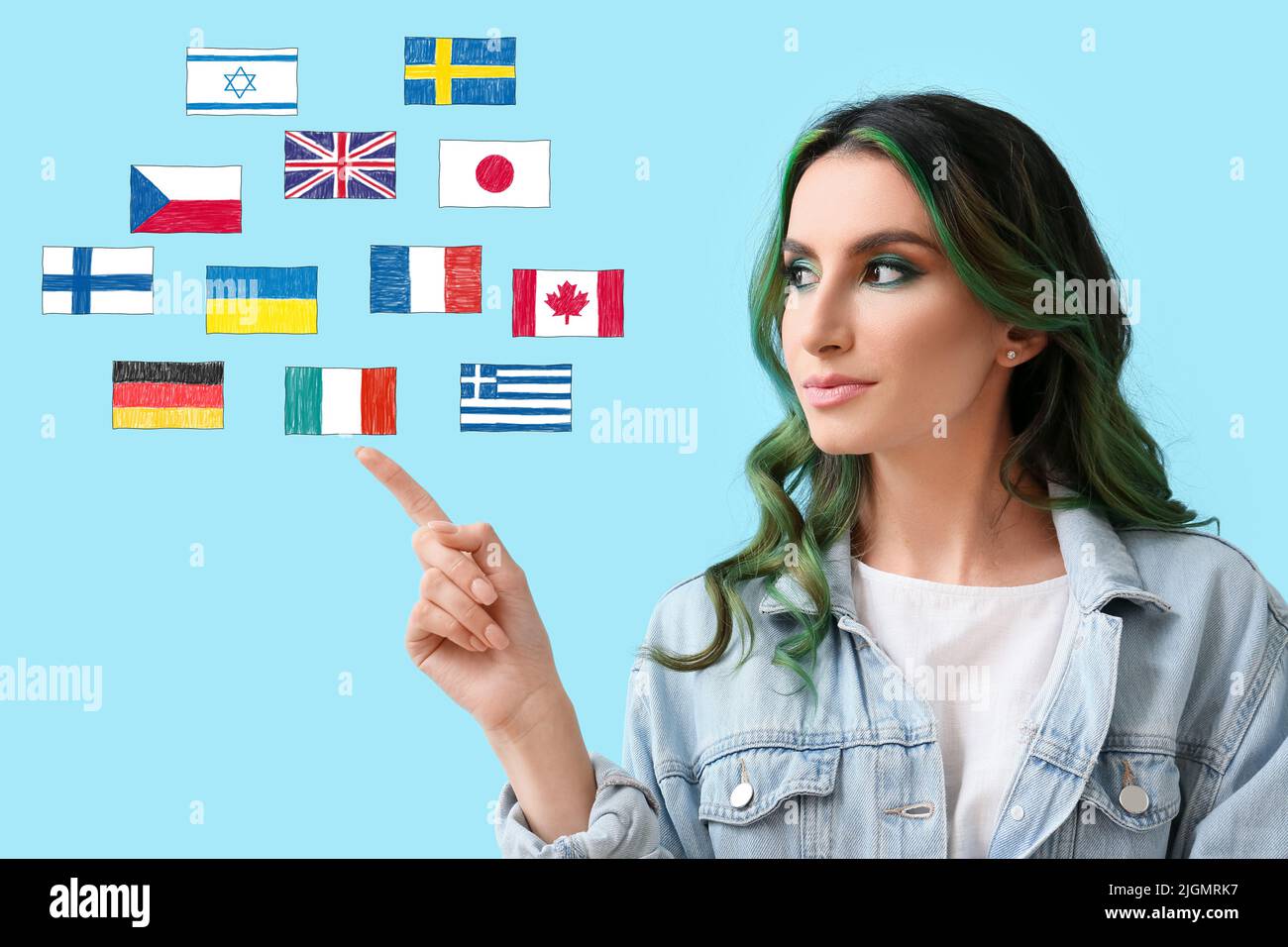 Pretty young woman and different flags on light blue background ...