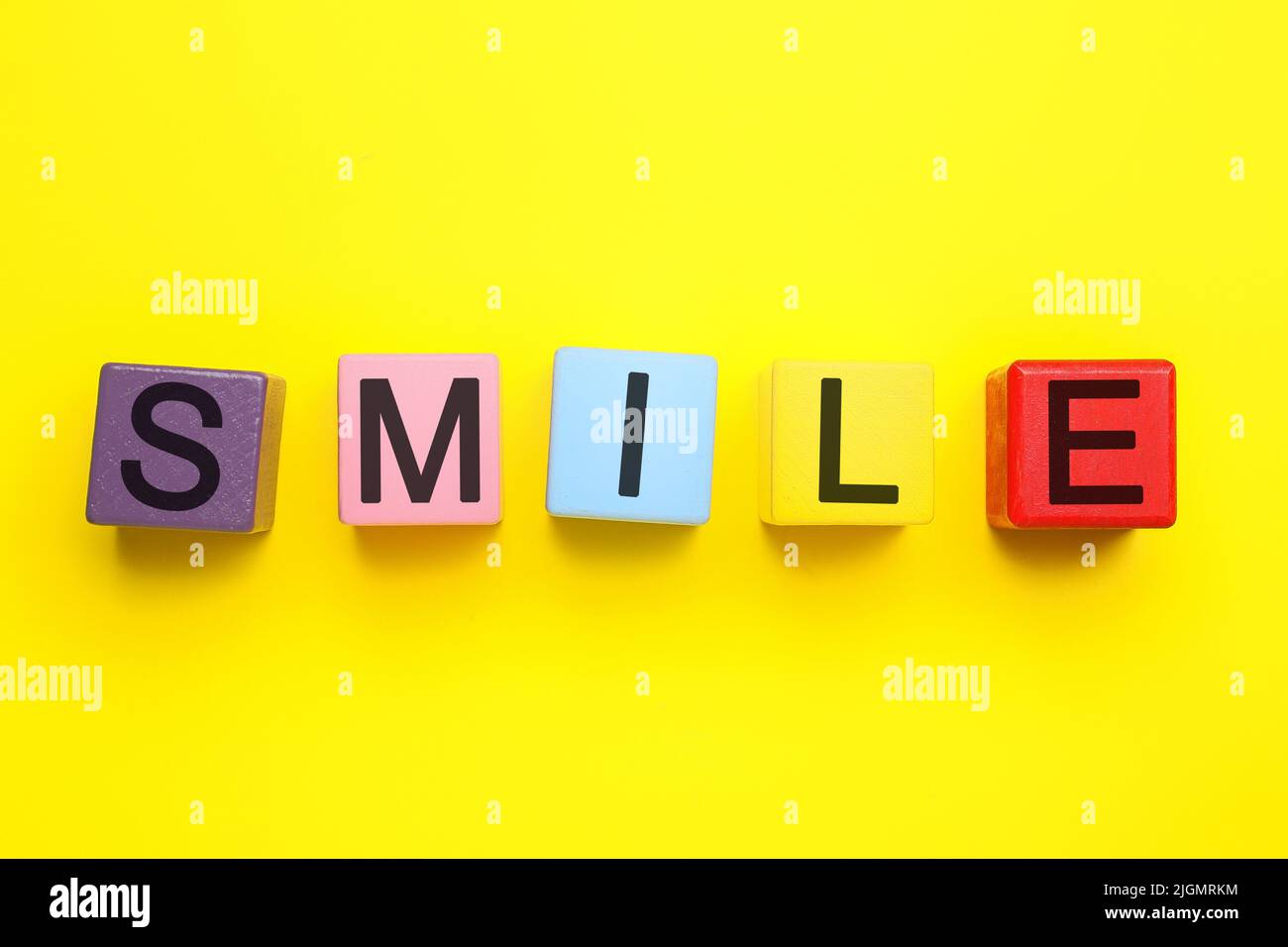 Bright cubes with word SMILE on yellow background Stock Photo - Alamy