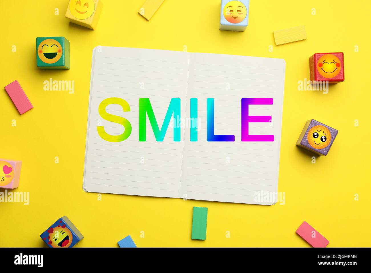 Open notebook with word SMILE and cubes with emoticons on yellow ...