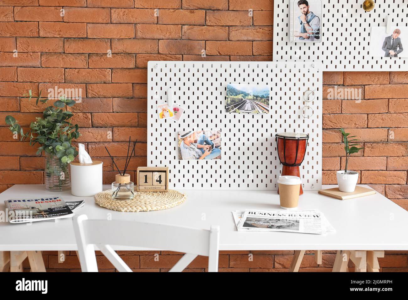 Workplace with peg boards, drum, tissue box and coffee cup near brick ...