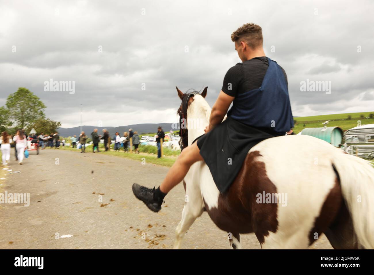 A young man trotting along the road on a coloured gypsy cob horse ...