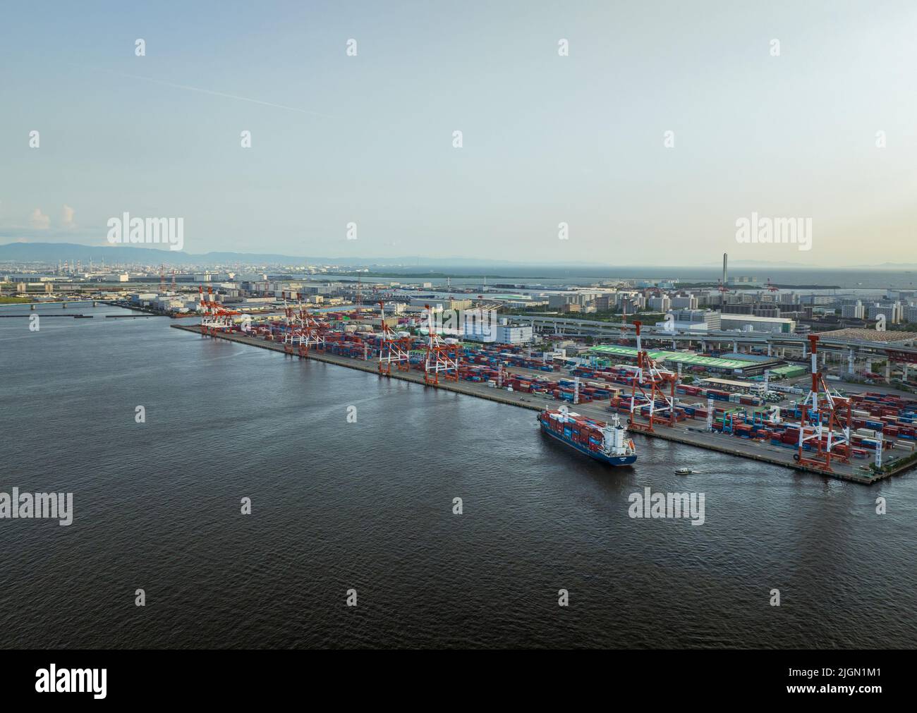 Container ship maneuvers into docking position under loading cranes ...