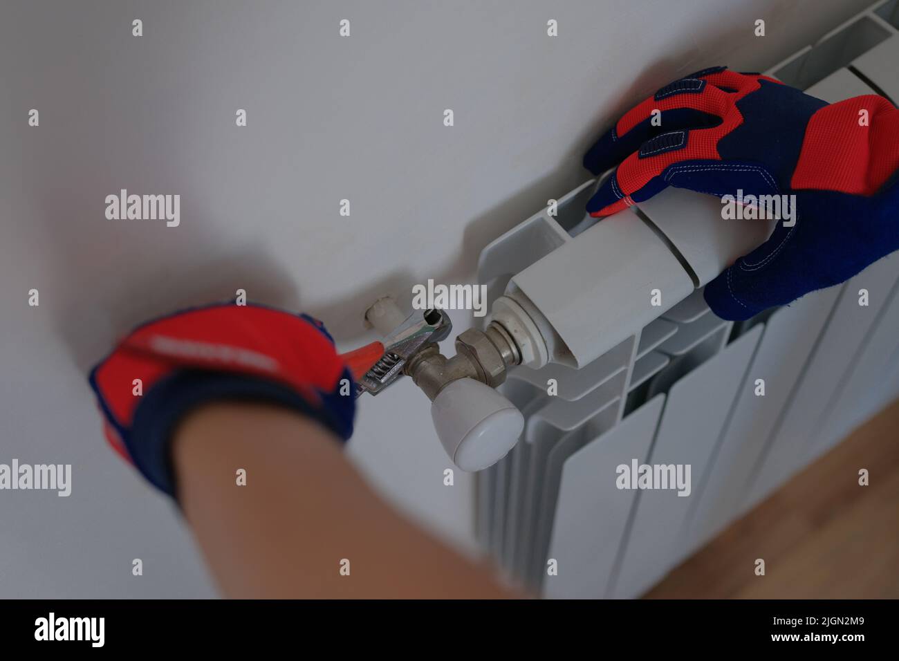 Male plumber installing heating radiator using pipe wrench Stock Photo ...