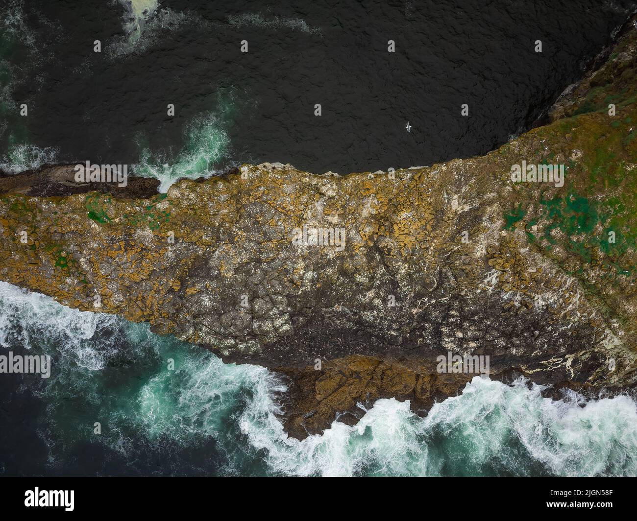 A small uninhabited island in the ocean. The white foamy waves of the ...