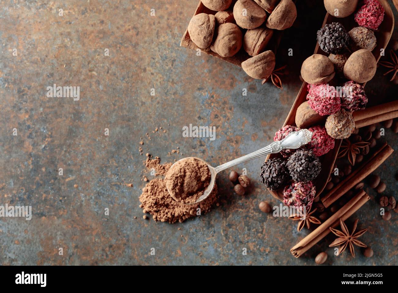 Chocolate truffles and spoon with cocoa powder. Candies with cinnamon, anise, and coffee beans ...