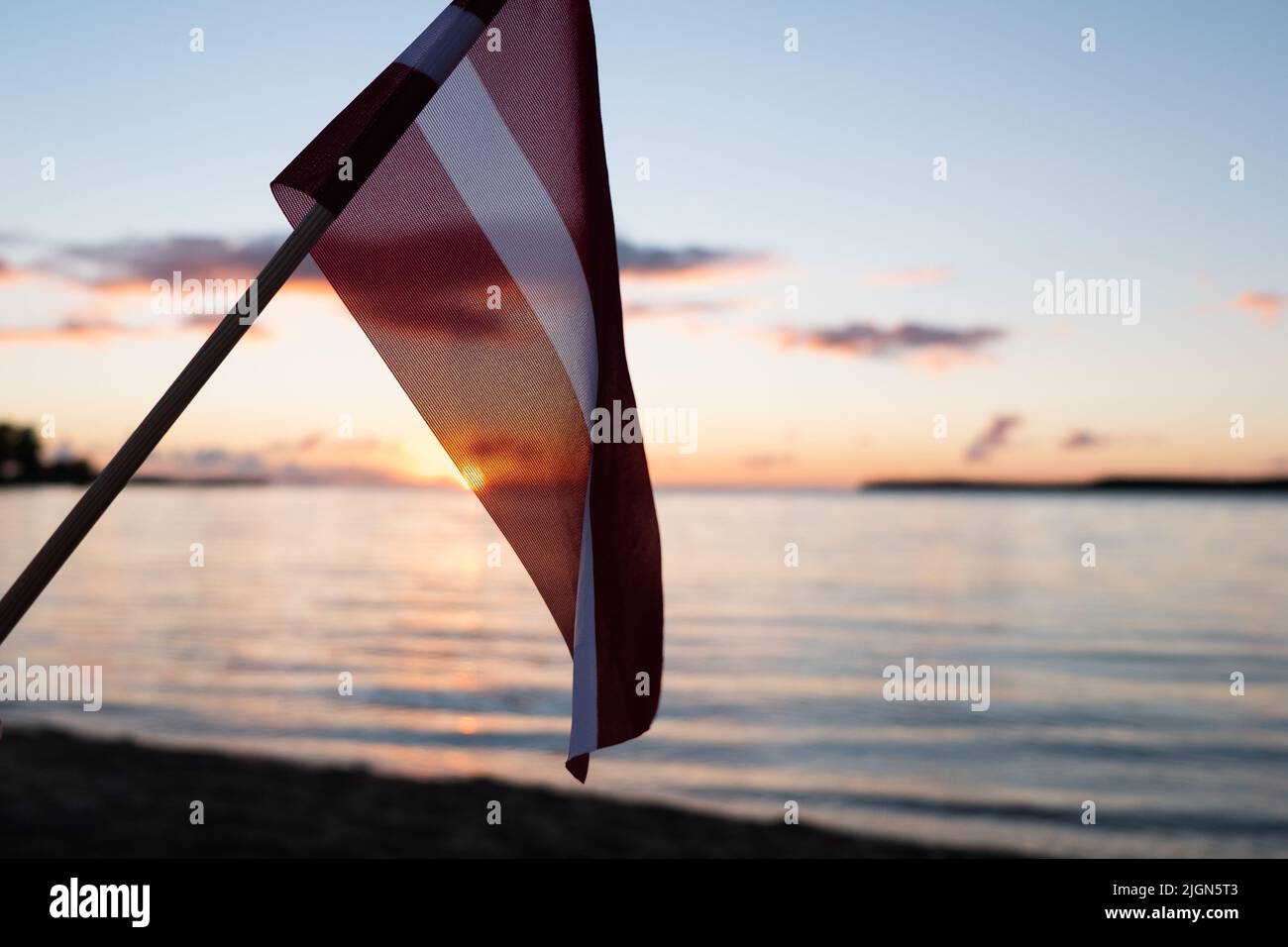 Flag of Latvia on evening beach background. Latvian flag waving at sunset Stock Photo - Alamy