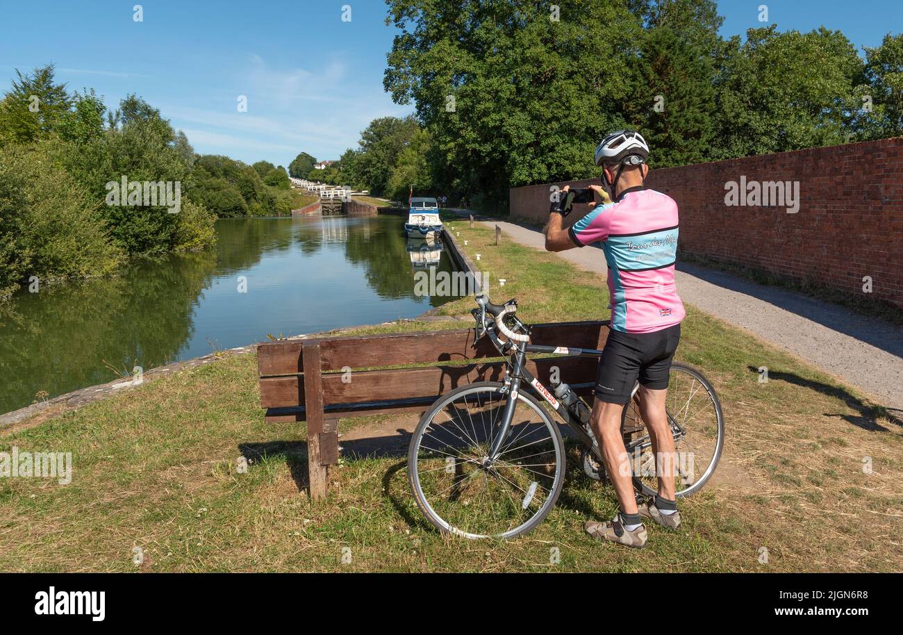 Devizes, Wiltshire, England, UK. 2022. Cyclist at Caen flight of locks ...