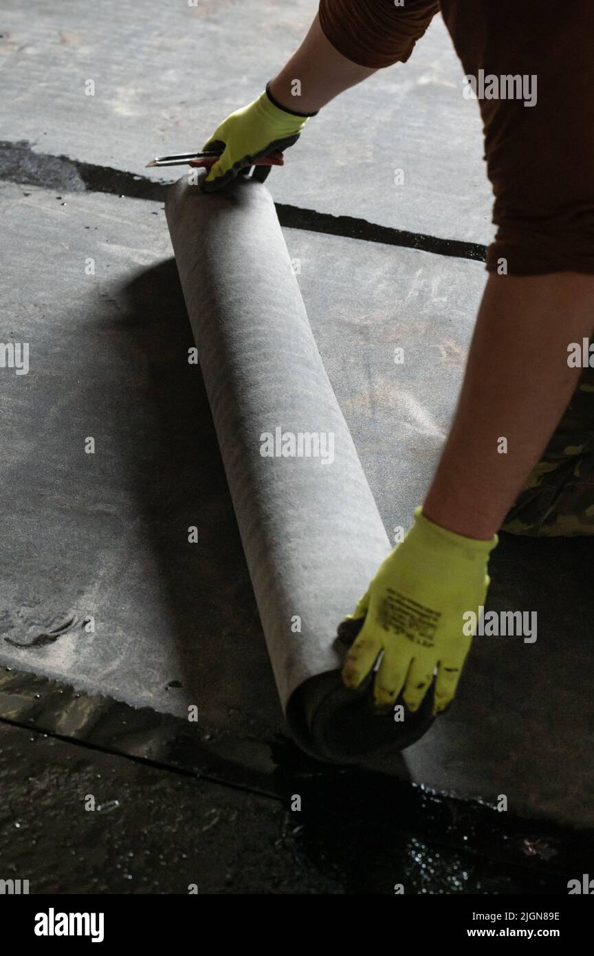 The worker untwists the roll of waterproofing and fastens it to the ...