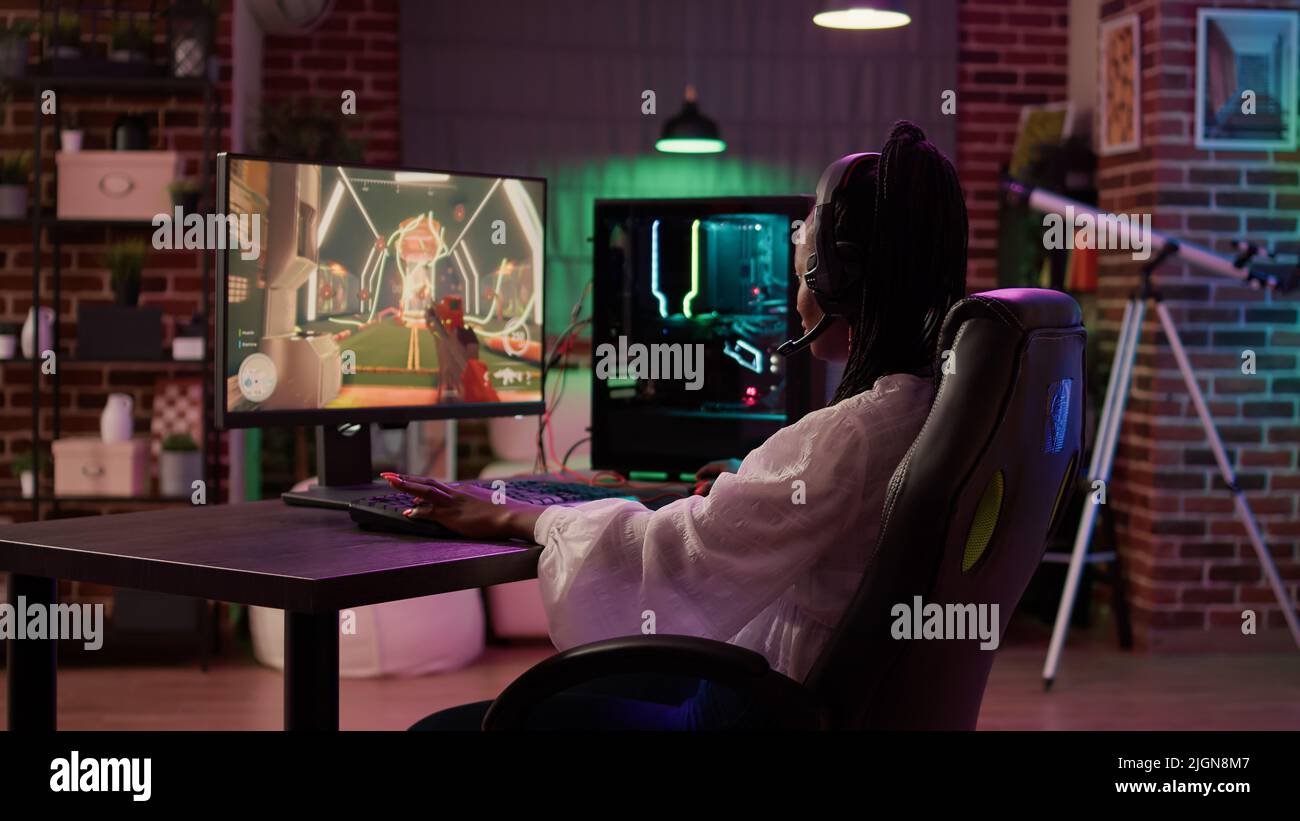 Over shoulder view of woman streaming first person shooter doing ...