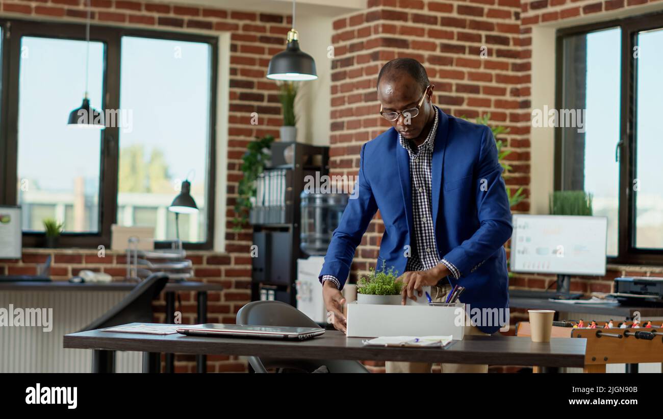 Disappointed sad person getting fired from work and packing things ...