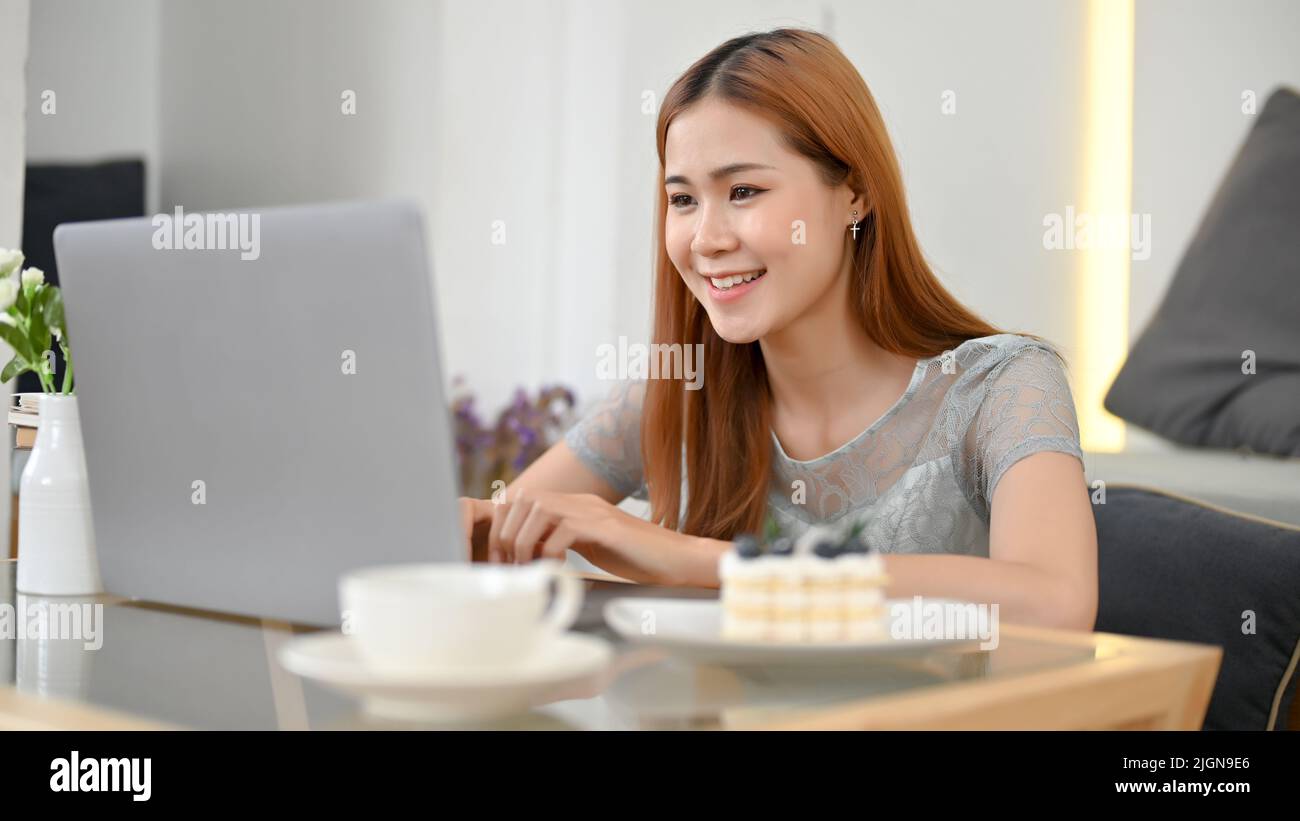 Attractive millennial Asian female freelancer or college student remote woking at the cafe ...