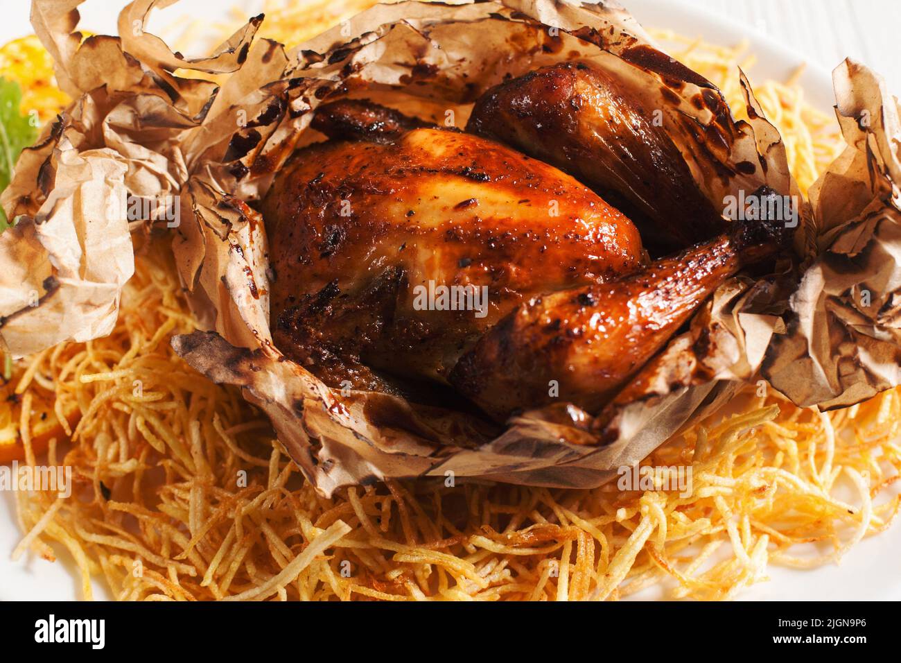 Baked chicken served in paper with fried potato Stock Photo - Alamy