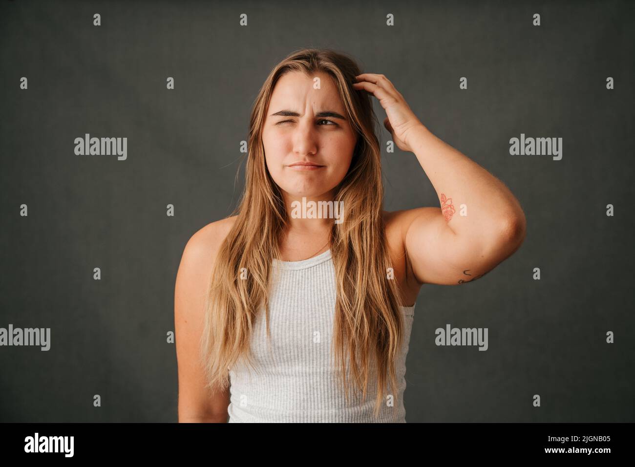 Young blond female scratching her head and thinking Stock Photo - Alamy