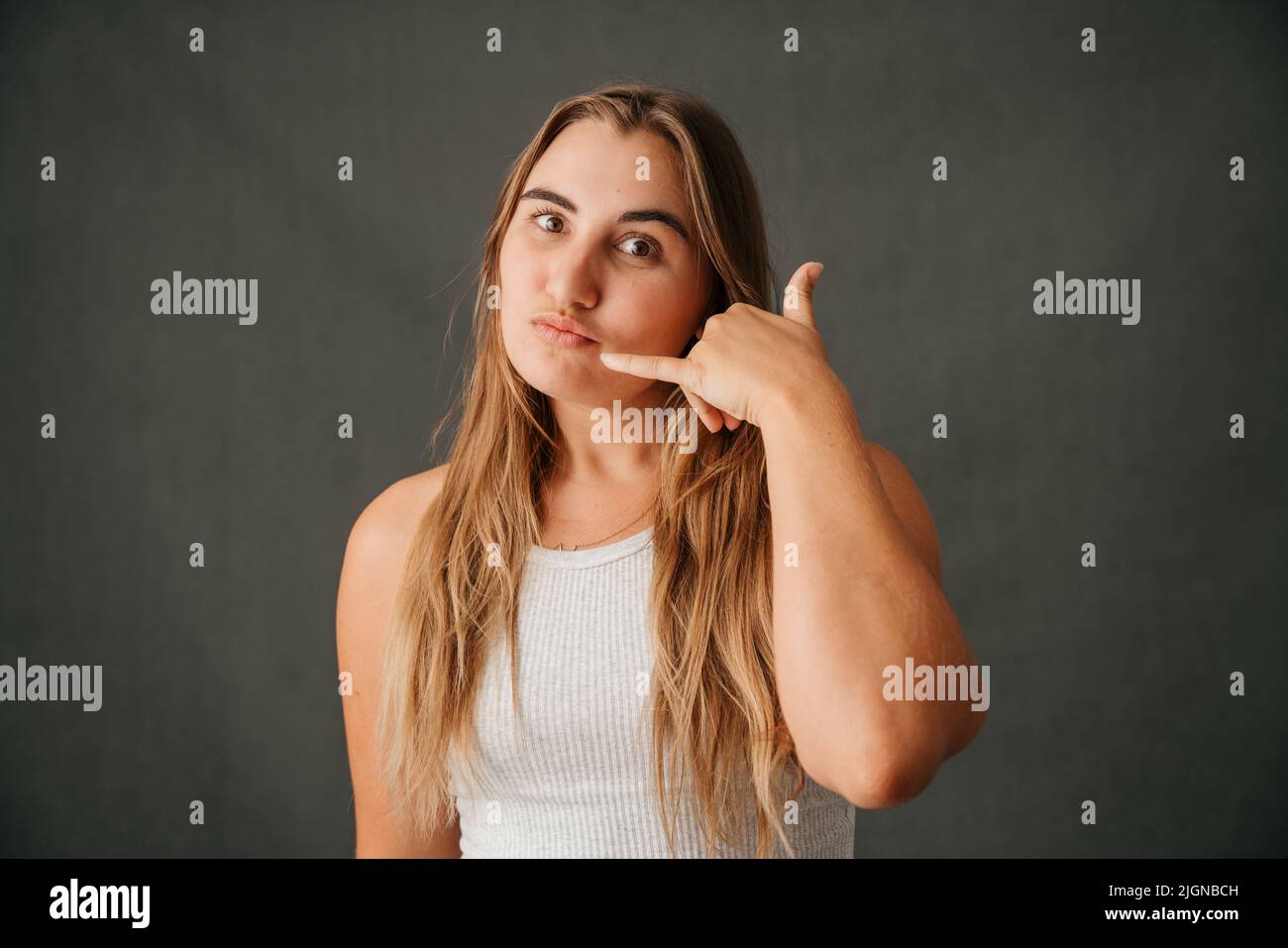 Attractive blond female making the give me a call sign to her friend ...