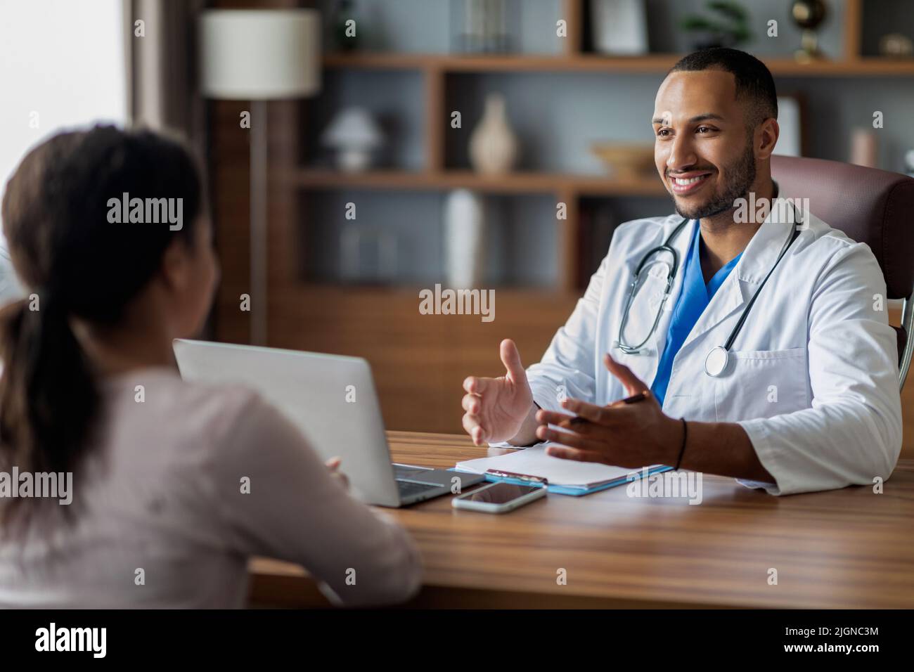 Positive arab doctor consulting african american lady patient Stock ...