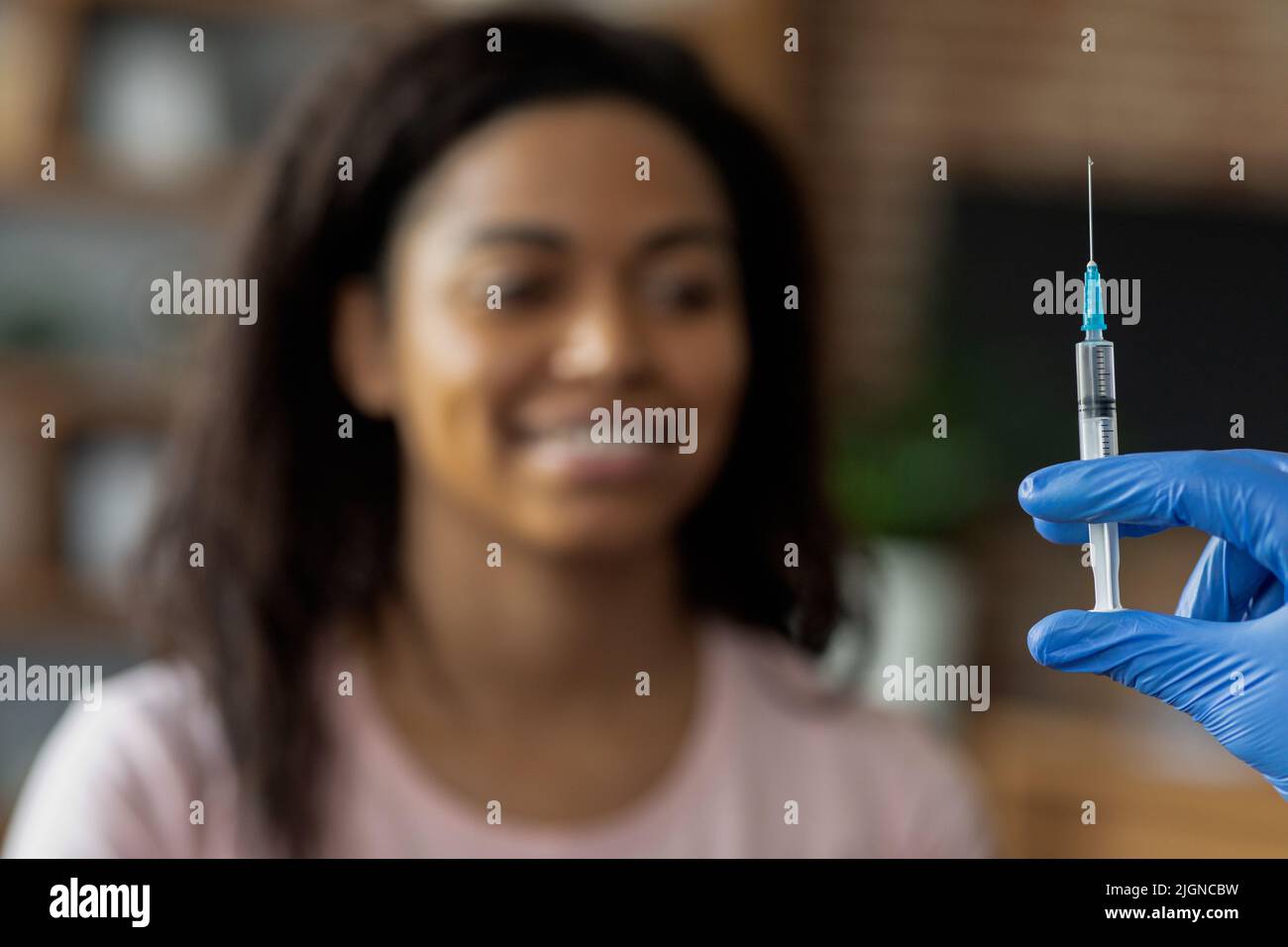 Syringe in doctor hand over smiling black woman patient Stock Photo - Alamy