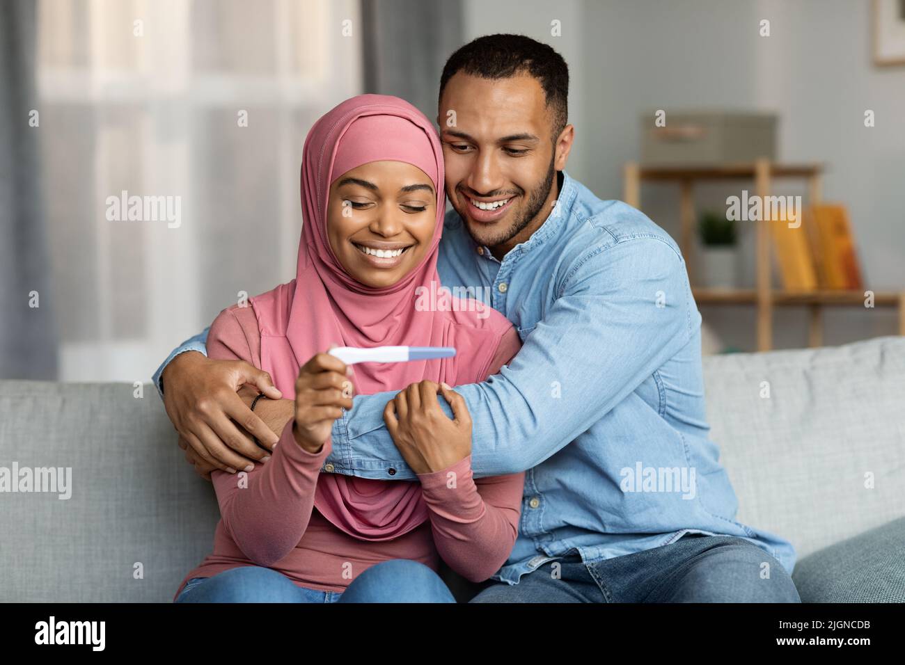 Married Islamic Couple Sitting On Couch, Holding Pregnancy Test And ...