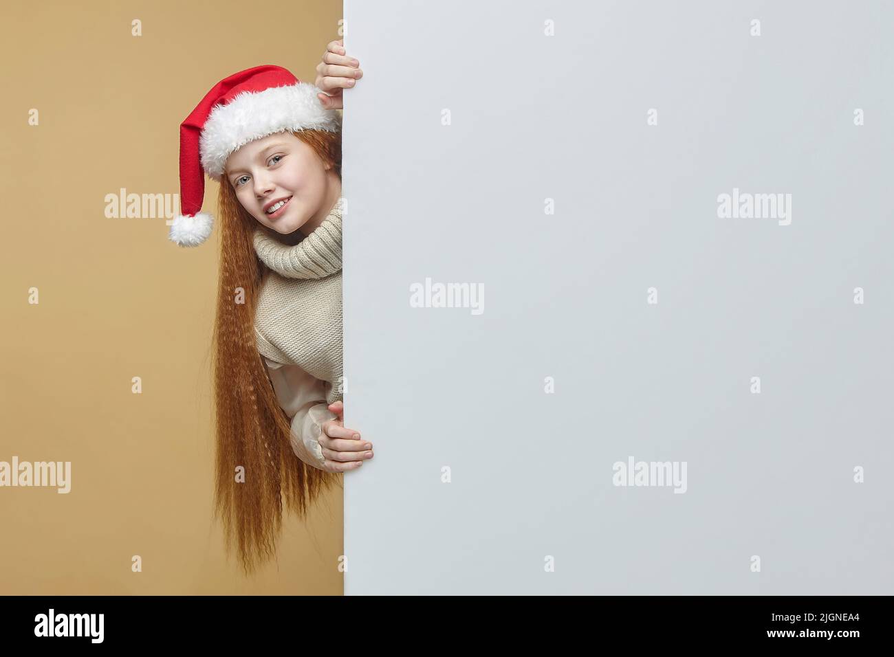 happy red-haired girl in a Santa hat with a white Billboard on which ...