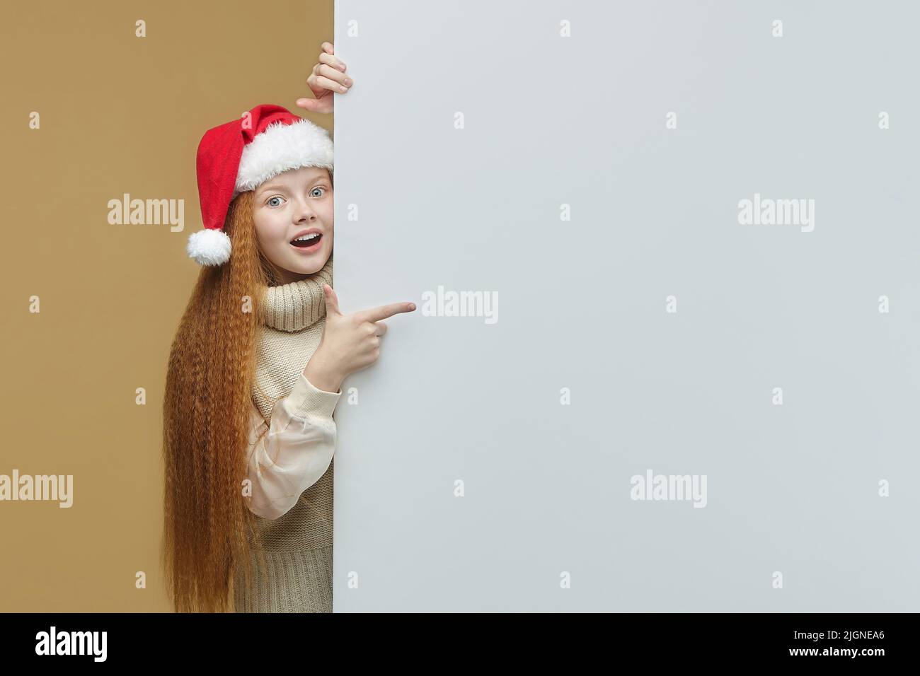 happy red-haired girl in a Santa hat with a white Billboard on which ...
