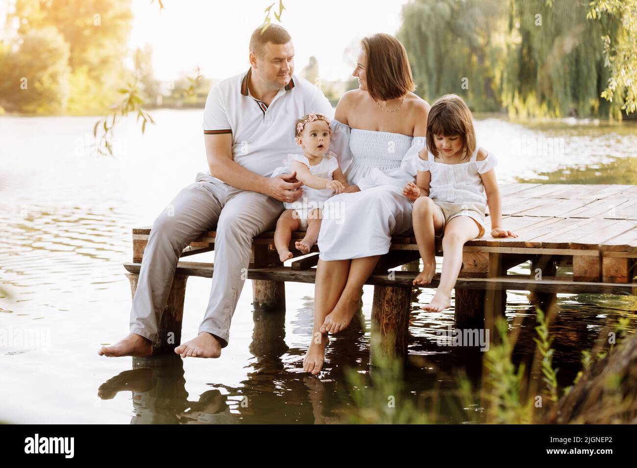 Happy young family near lake, pond on summer. Mother, father and two ...