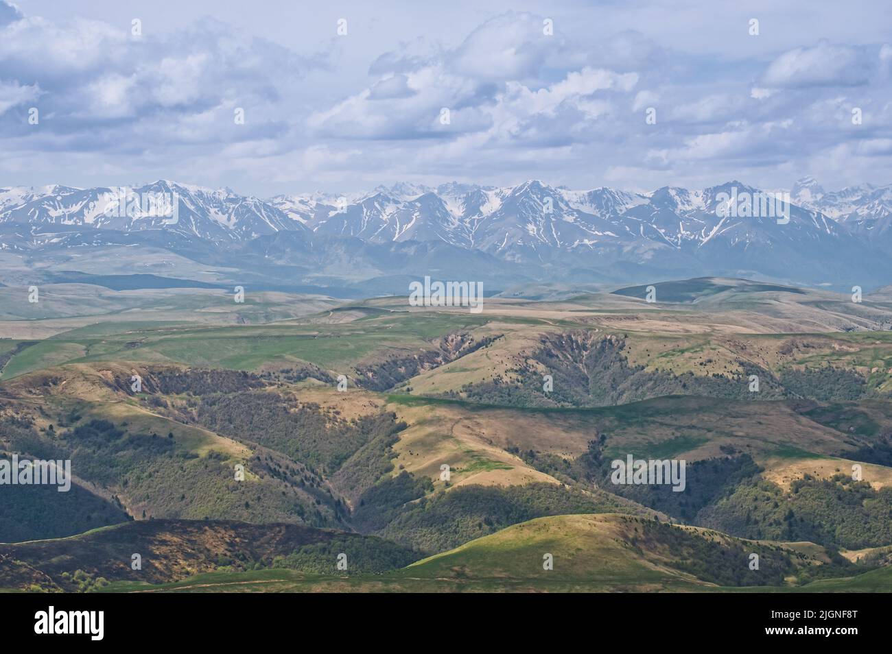Atmospheric alpine landscape with mountain range and green hills under ...