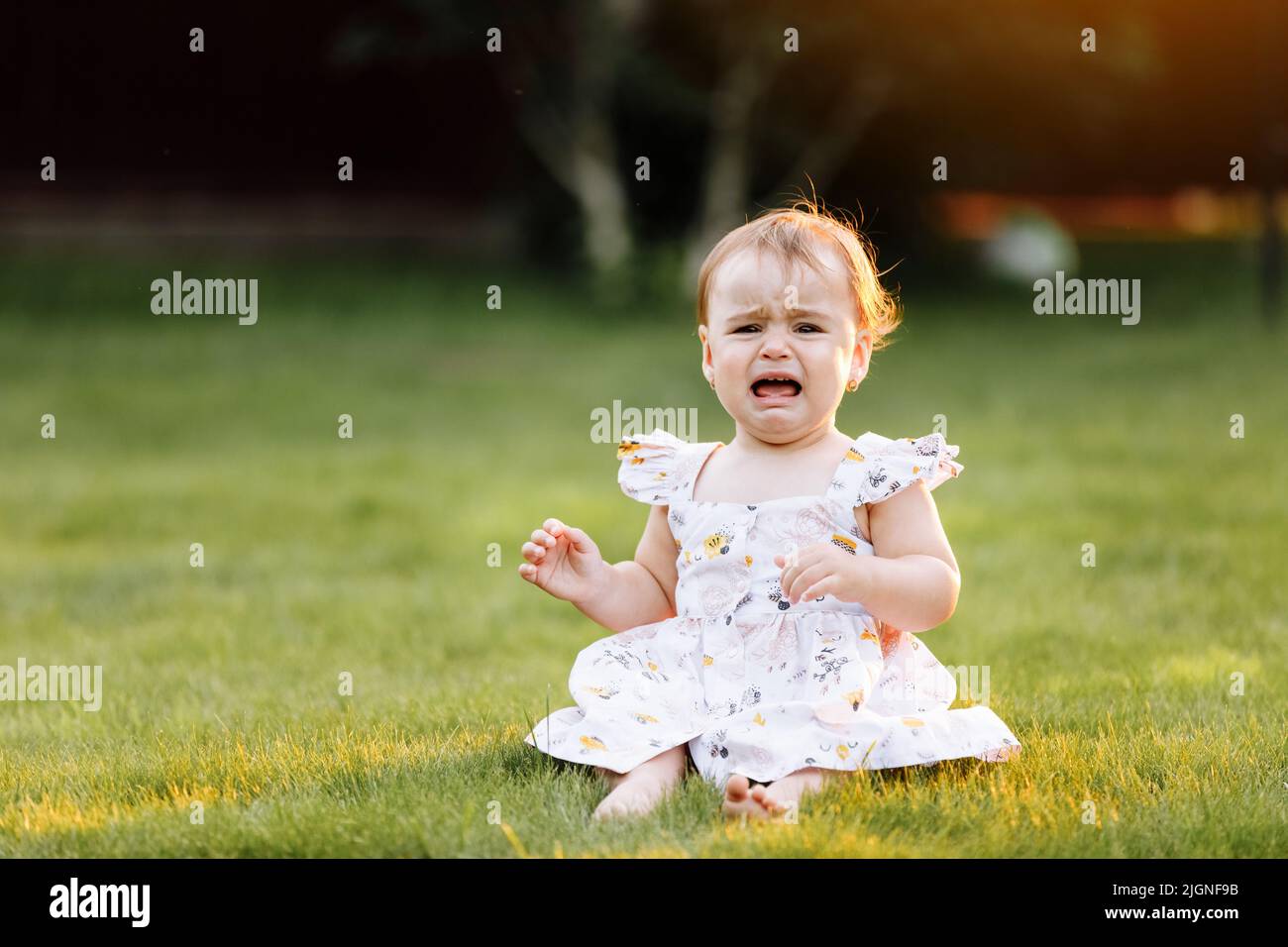 crying baby toddler girl on grass outdoors. Child feelings and emotions ...