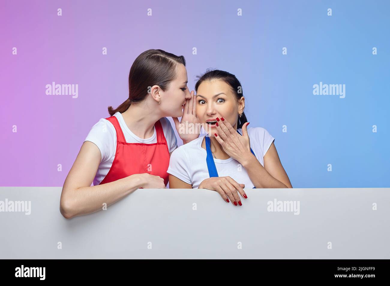 two girls in aprons pose with a white Billboard. advertising concept ...