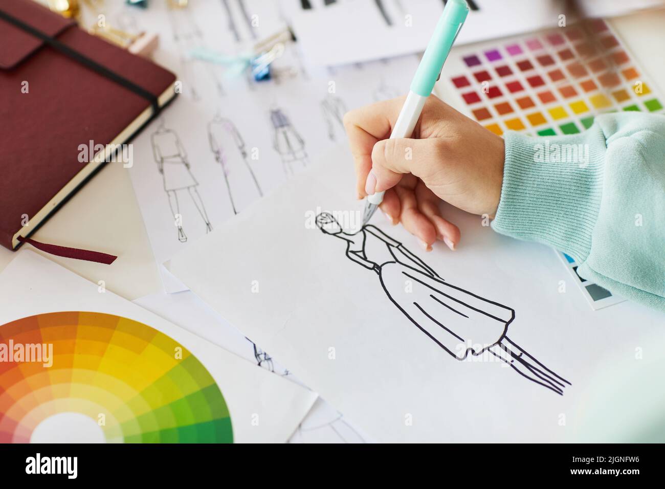 Close-up of unrecognizable female designer sitting at table with color ...