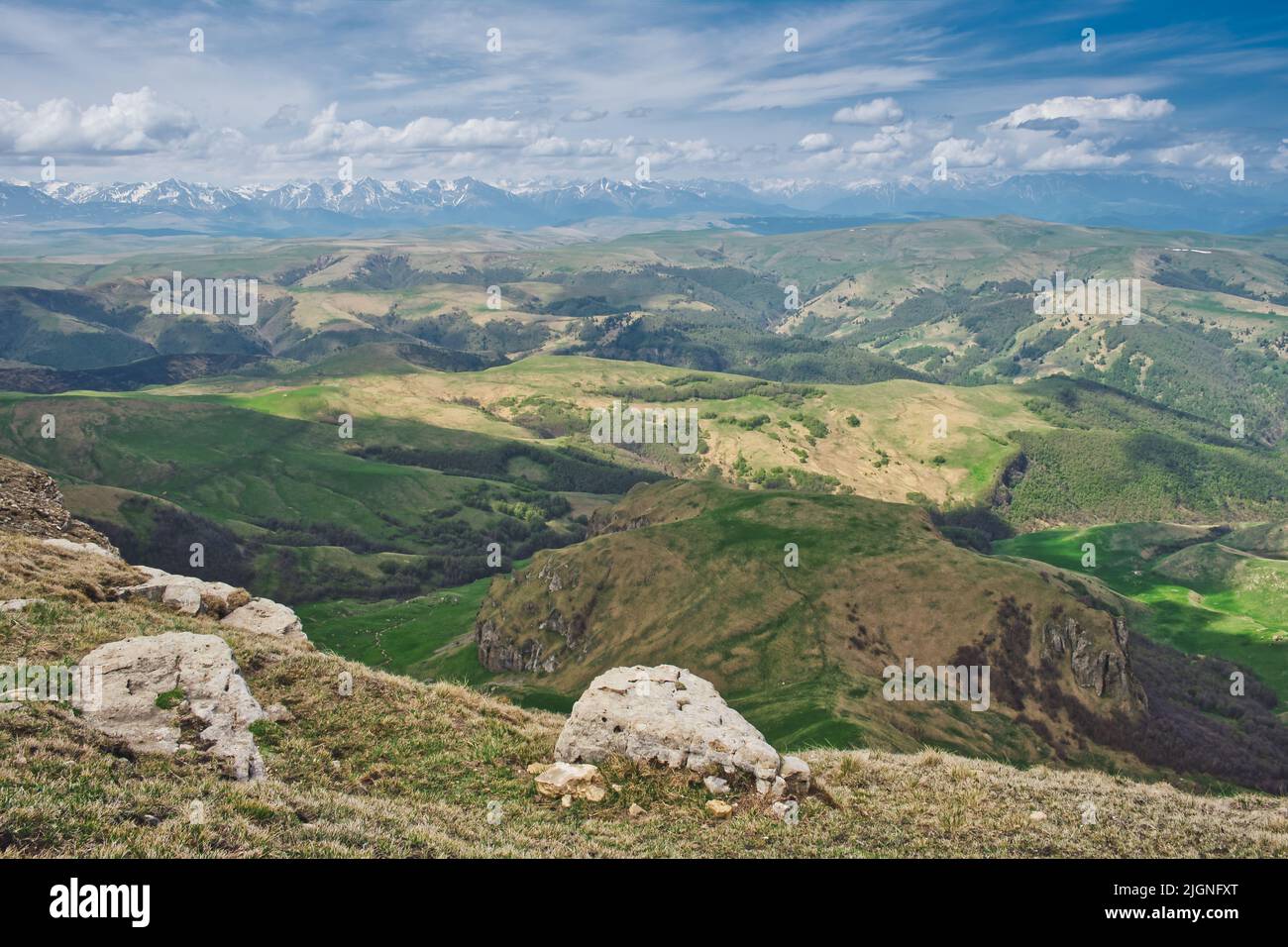 Atmospheric alpine landscape with mountain range and green hills under ...