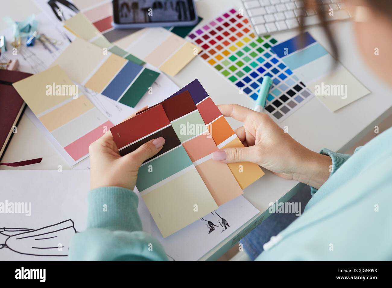 Over shoulder view of unrecognizable designer sitting at table and ...