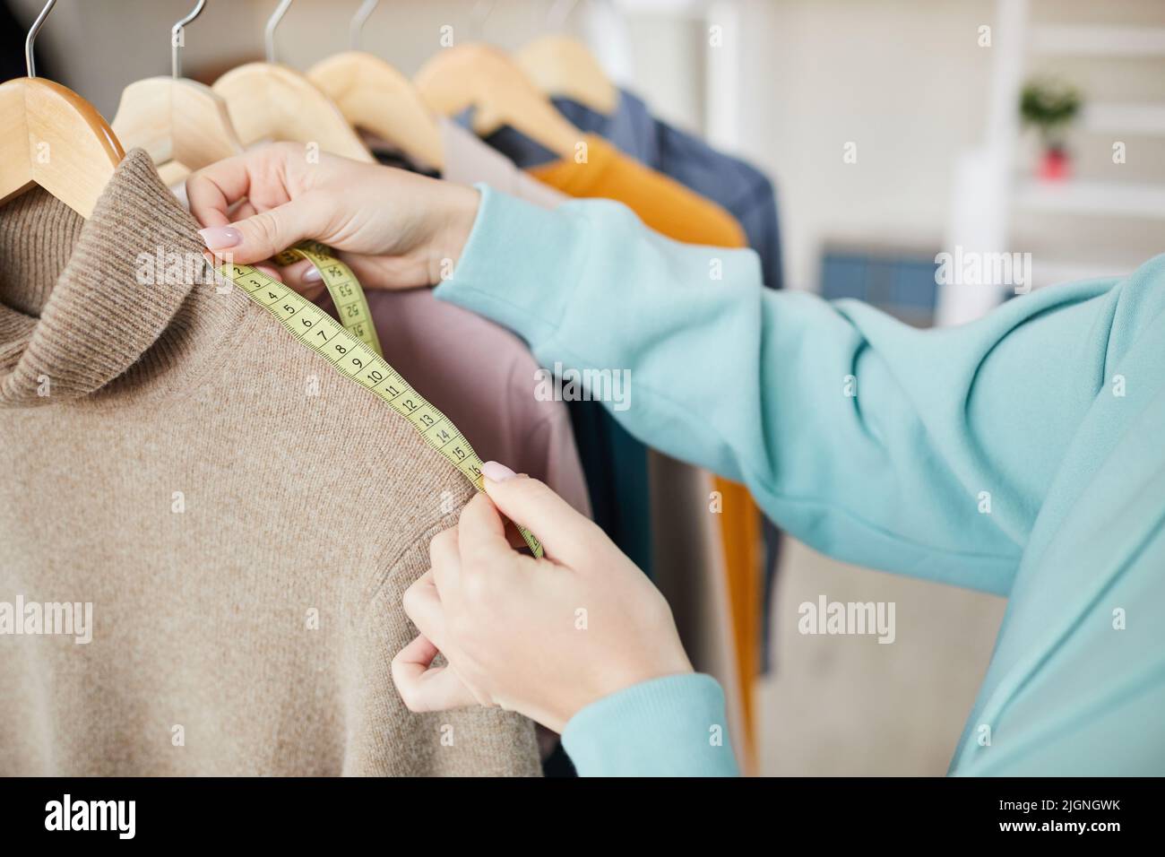 Close-up of unrecognizable female dressmaker in sweatshirt standing at ...