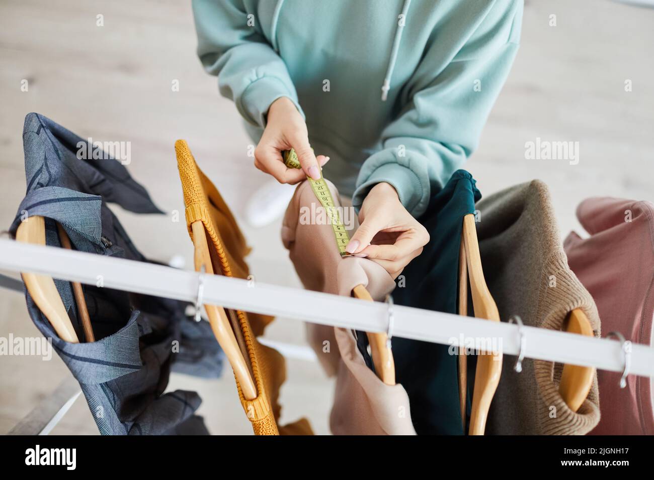 Above view of unrecognizable fashion designer standing at clothes rack ...
