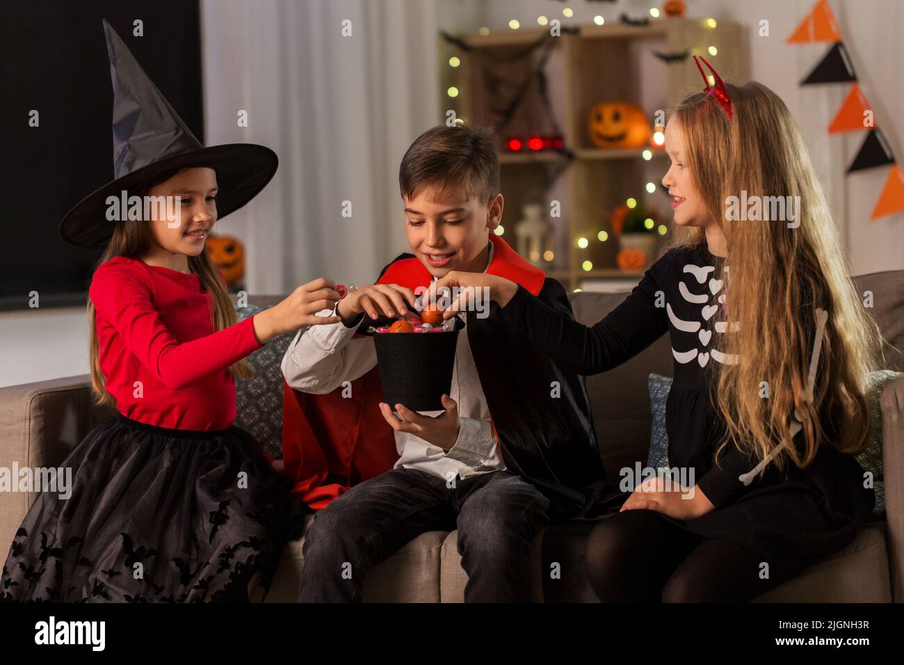 kids in halloween costumes sharing candies at home Stock Photo - Alamy