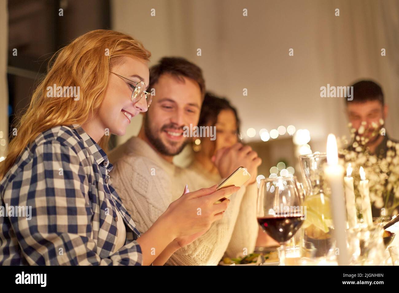 friends with cellphone having dinner party at home Stock Photo - Alamy