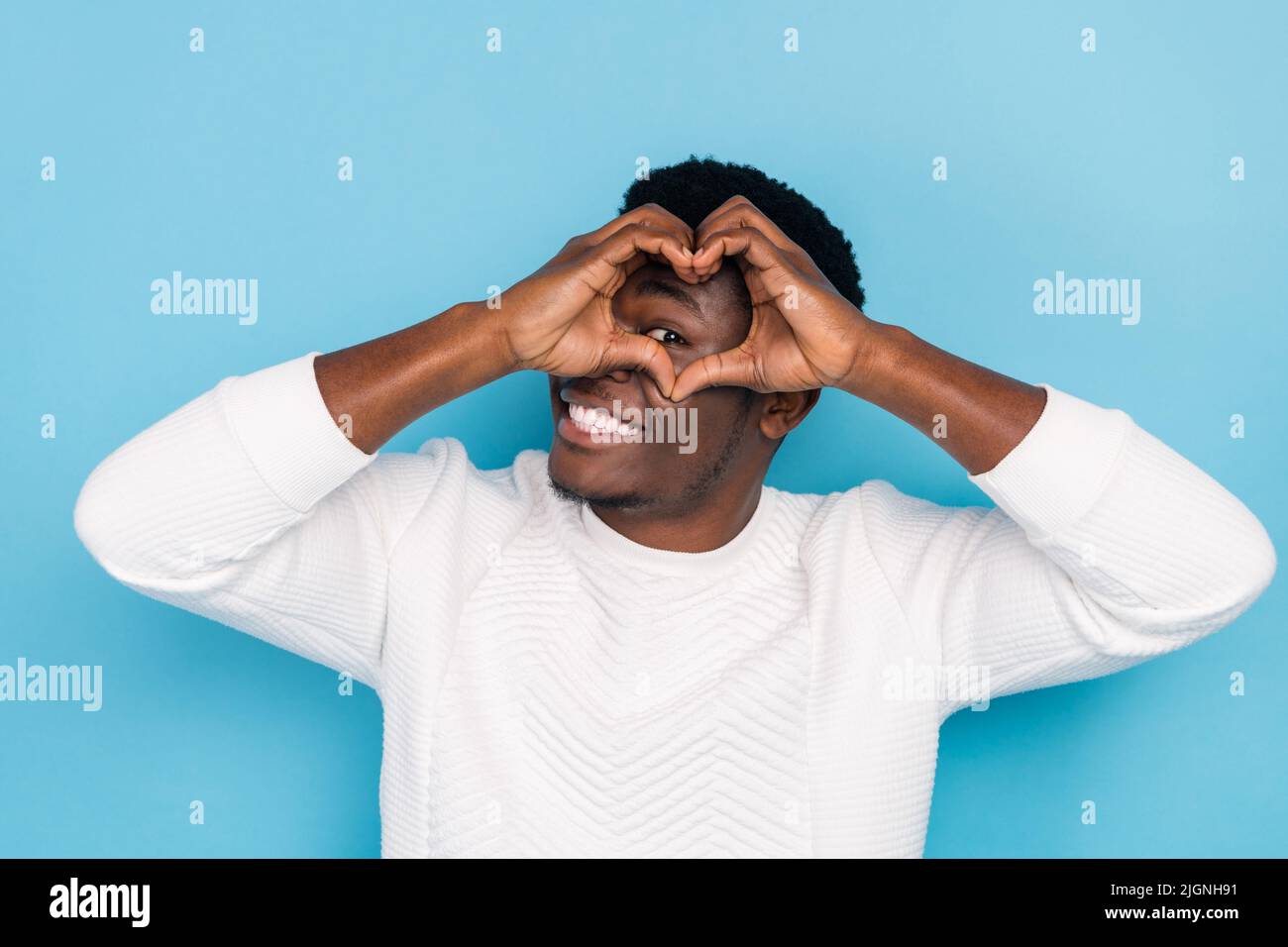Portrait of cheerful handsome young male showing heart symbol express ...