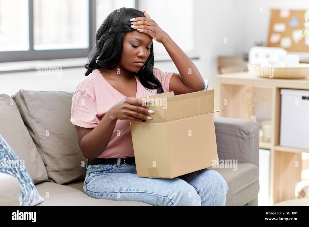 sad african american woman with parcel box at home Stock Photo - Alamy