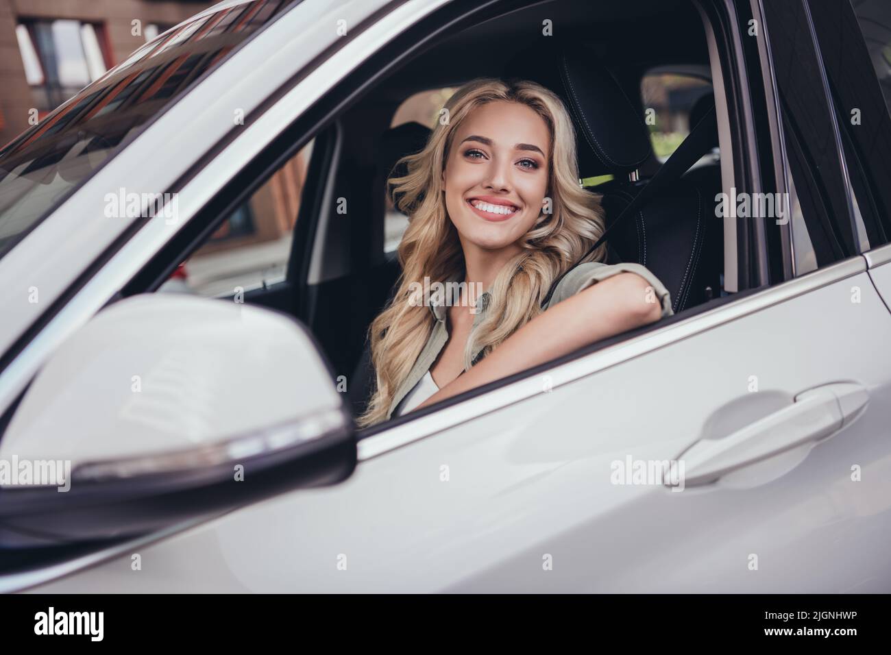 Photo of cheerful pretty lady sitting car driver seat look through ...