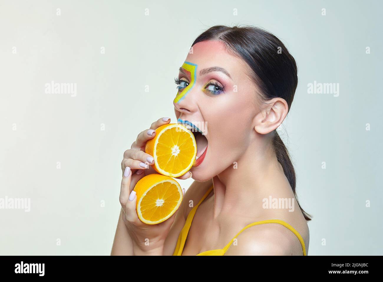 attractive young woman biting slice of orange Stock Photo - Alamy