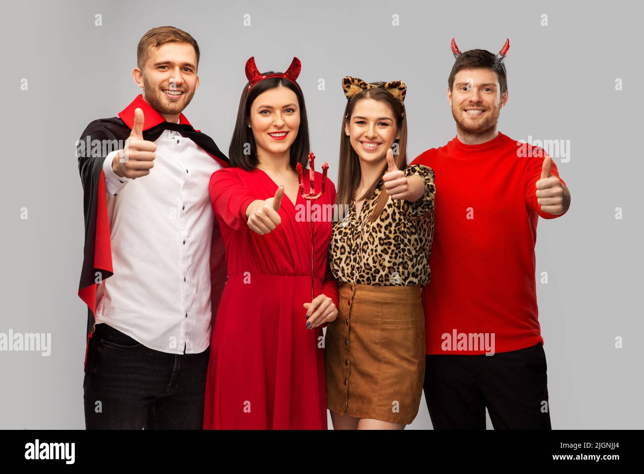 happy friends in halloween costumes snow thumbs up Stock Photo - Alamy