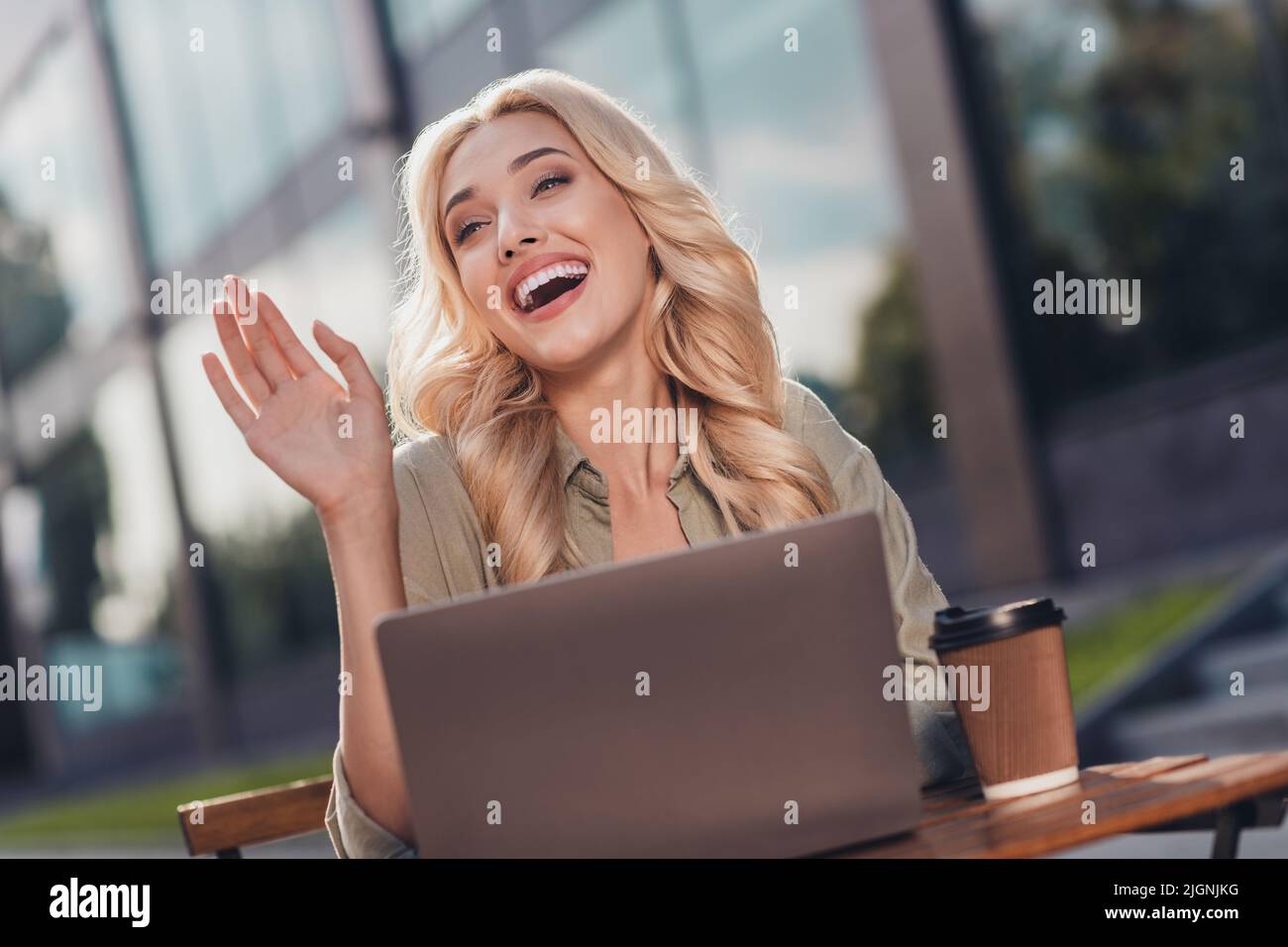 Portrait of attractive cheerful wavy haired girl using netbook waving ...