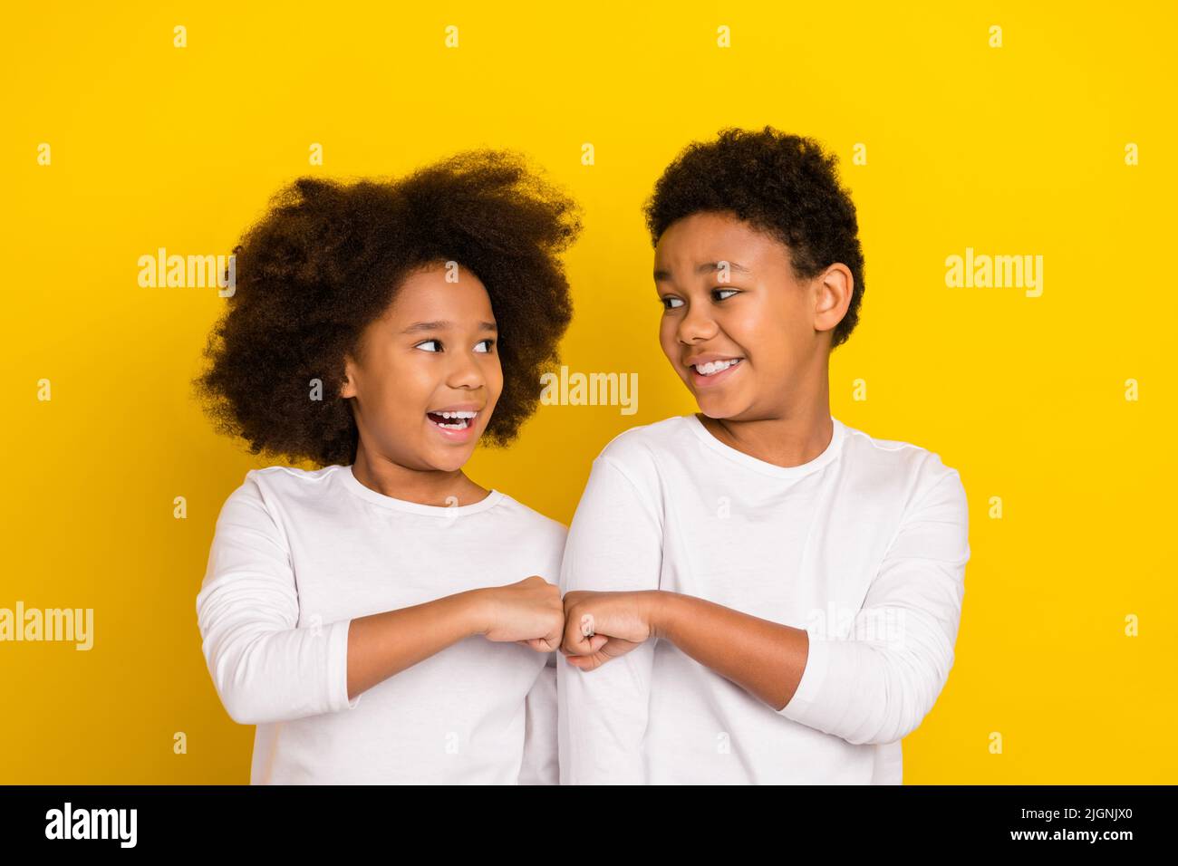 Photo of two positive siblings look each other hand give fist bump ...