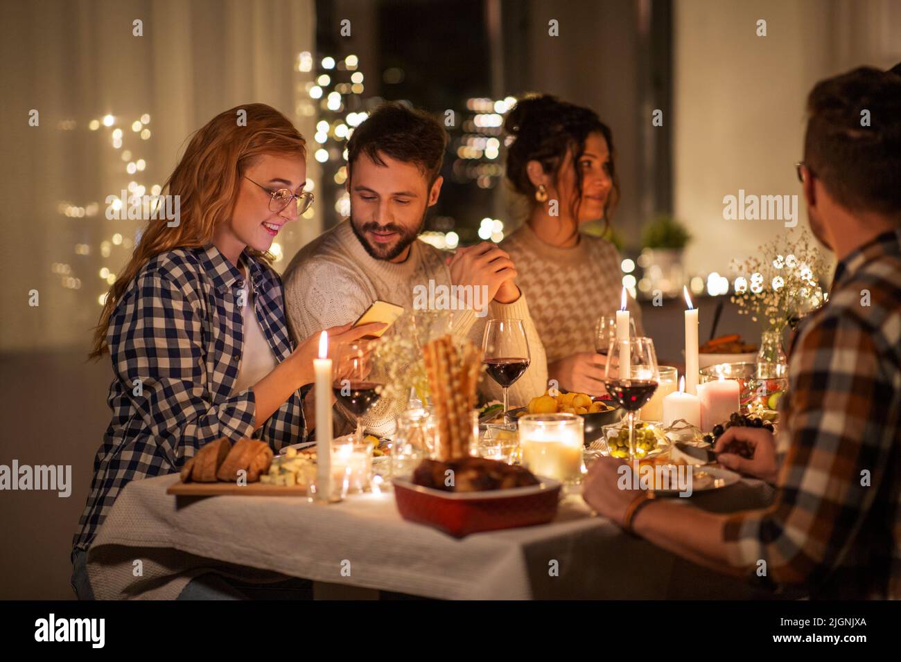 friends with cellphone having dinner party at home Stock Photo - Alamy
