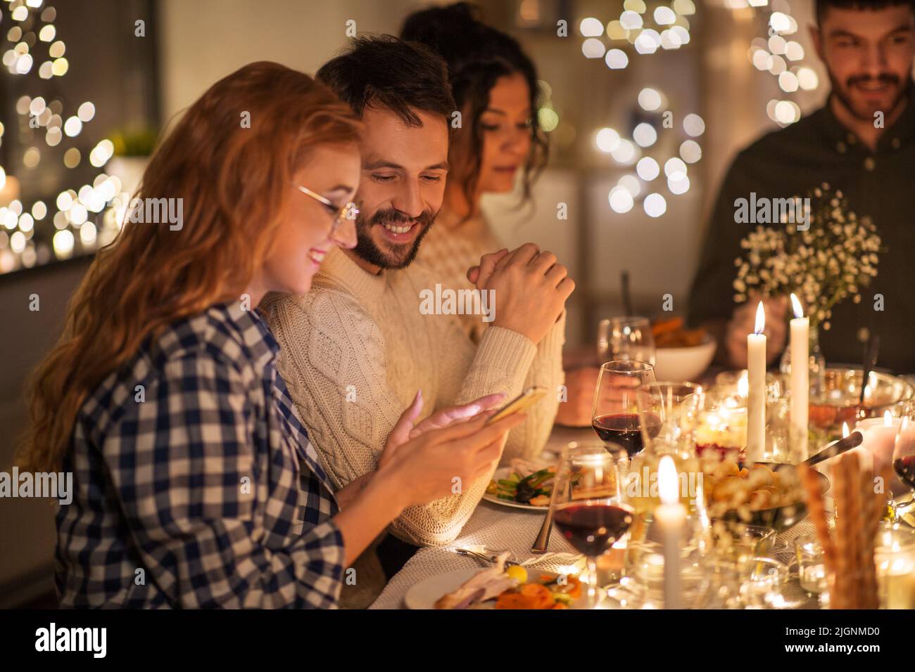 friends with cellphone having dinner party at home Stock Photo - Alamy