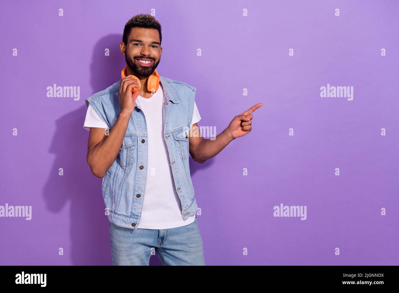 Photo of cute funky man wear jeans waistcoat headphones pointing finger ...