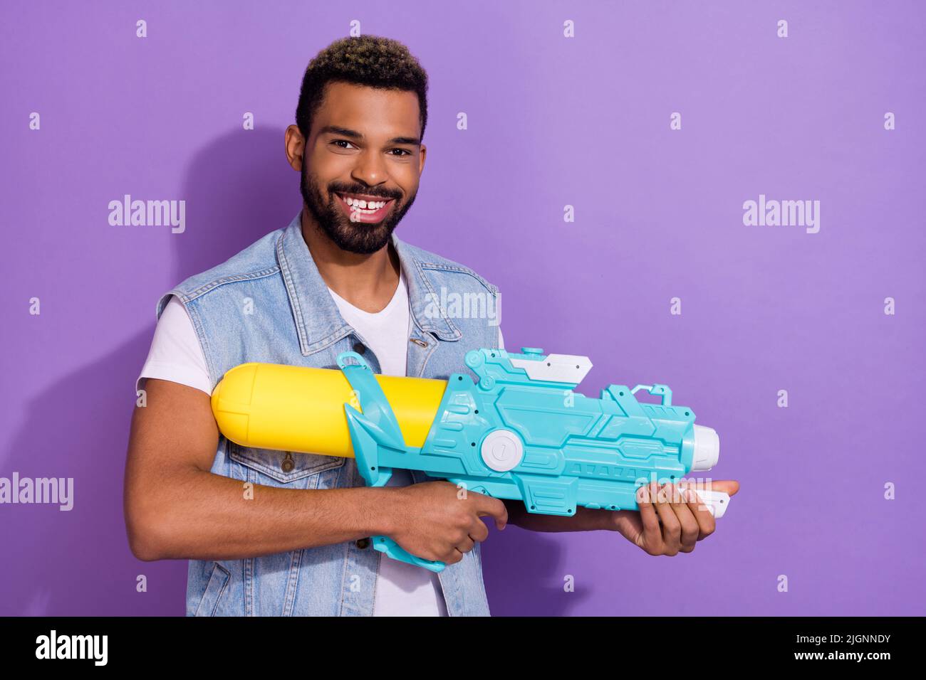 Photo of cool cheerful man wear jeans waistcoat pumping water gun empty ...